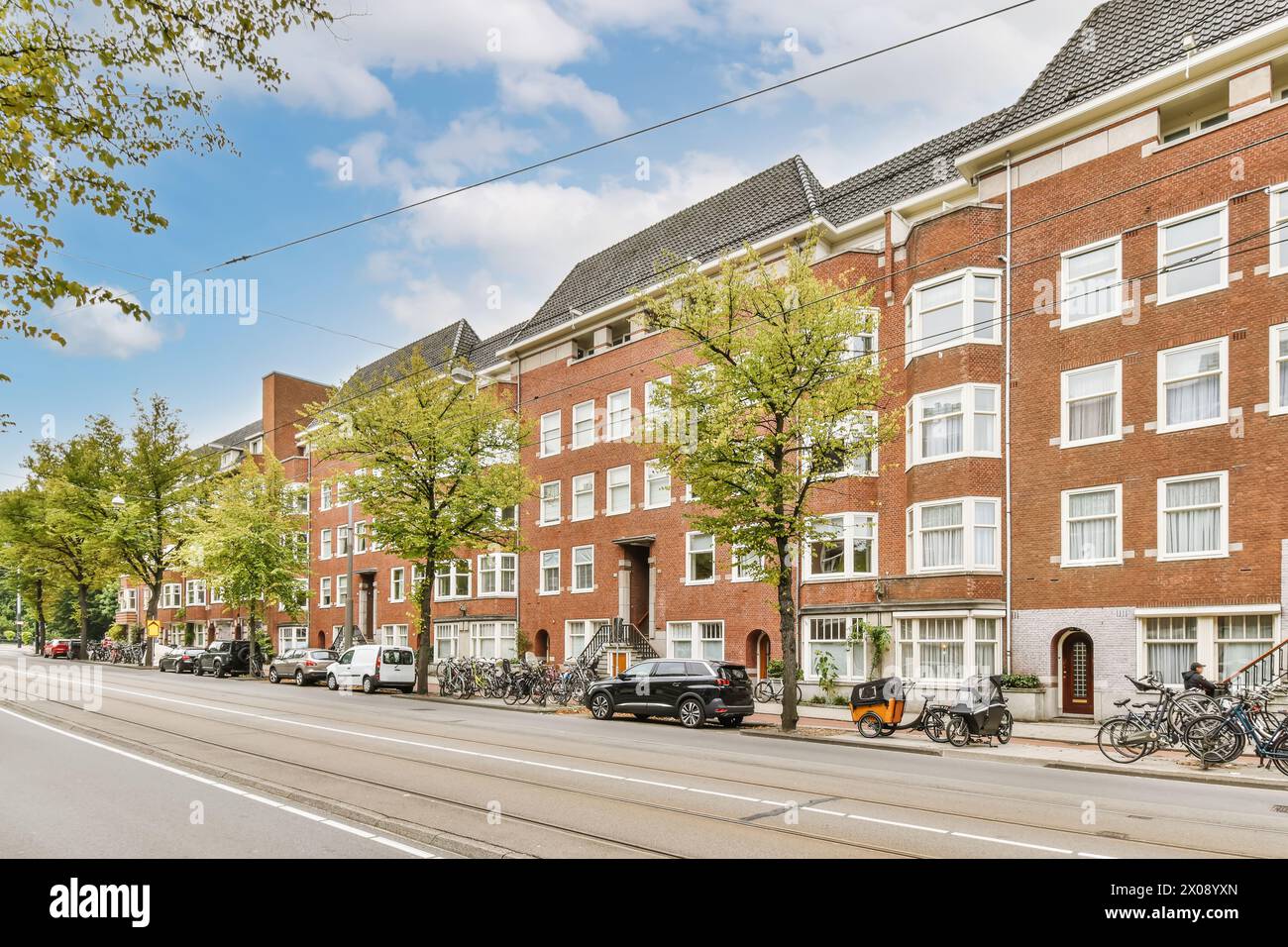 A serene street scene featuring a row of traditional brick apartment ...
