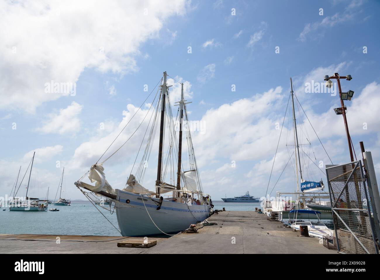 Sailing yachts moored at the jetty in Britannia Bay, Mustique Island ...