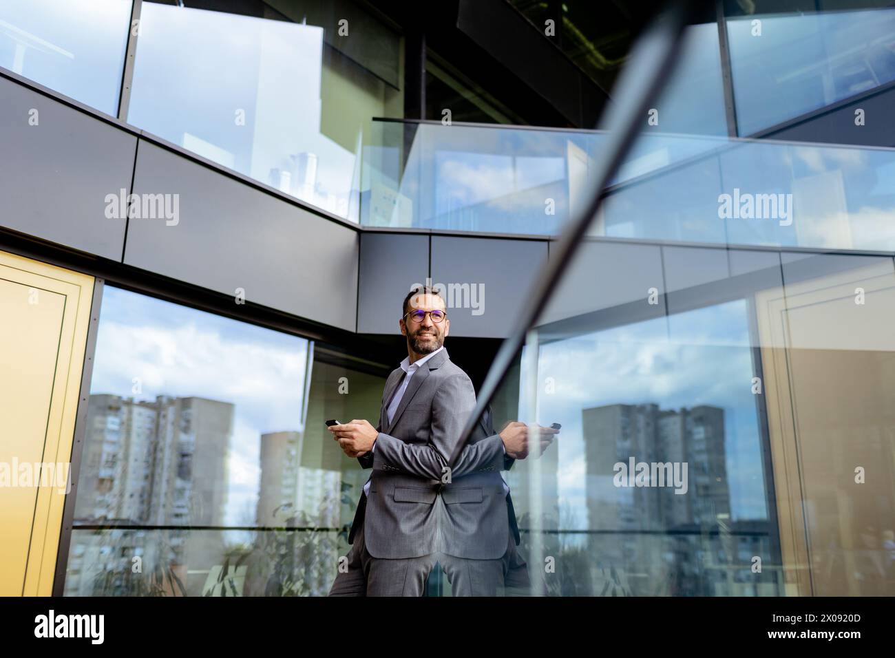 Suited man with arms crossed stands proudly before a sleek building ...