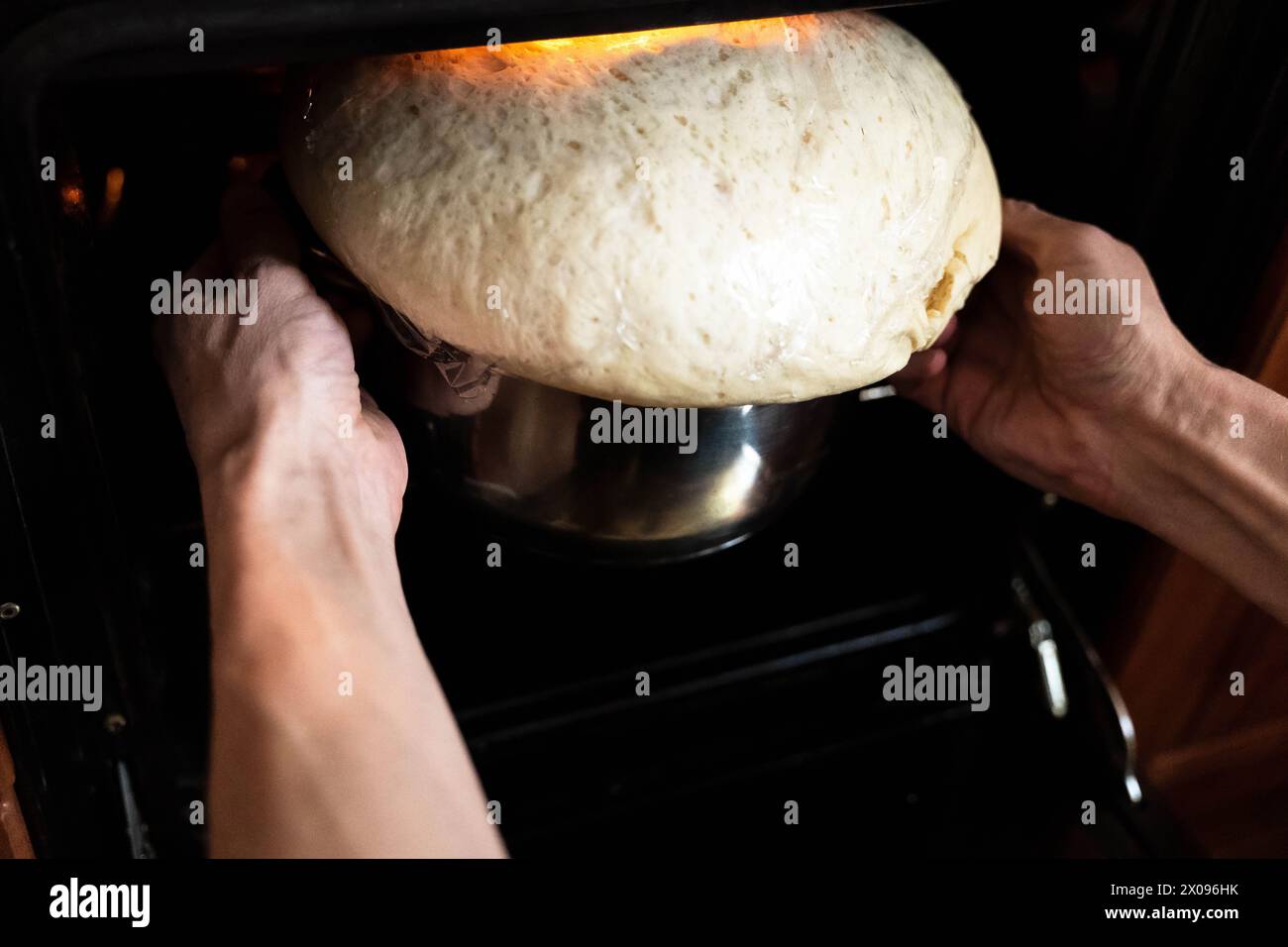 man's hands skillfully kneading dough for bread inside a hot oven, with ...