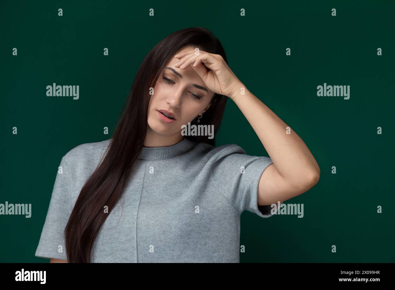 A distressed woman sitting with her head in her hands, showcasing ...