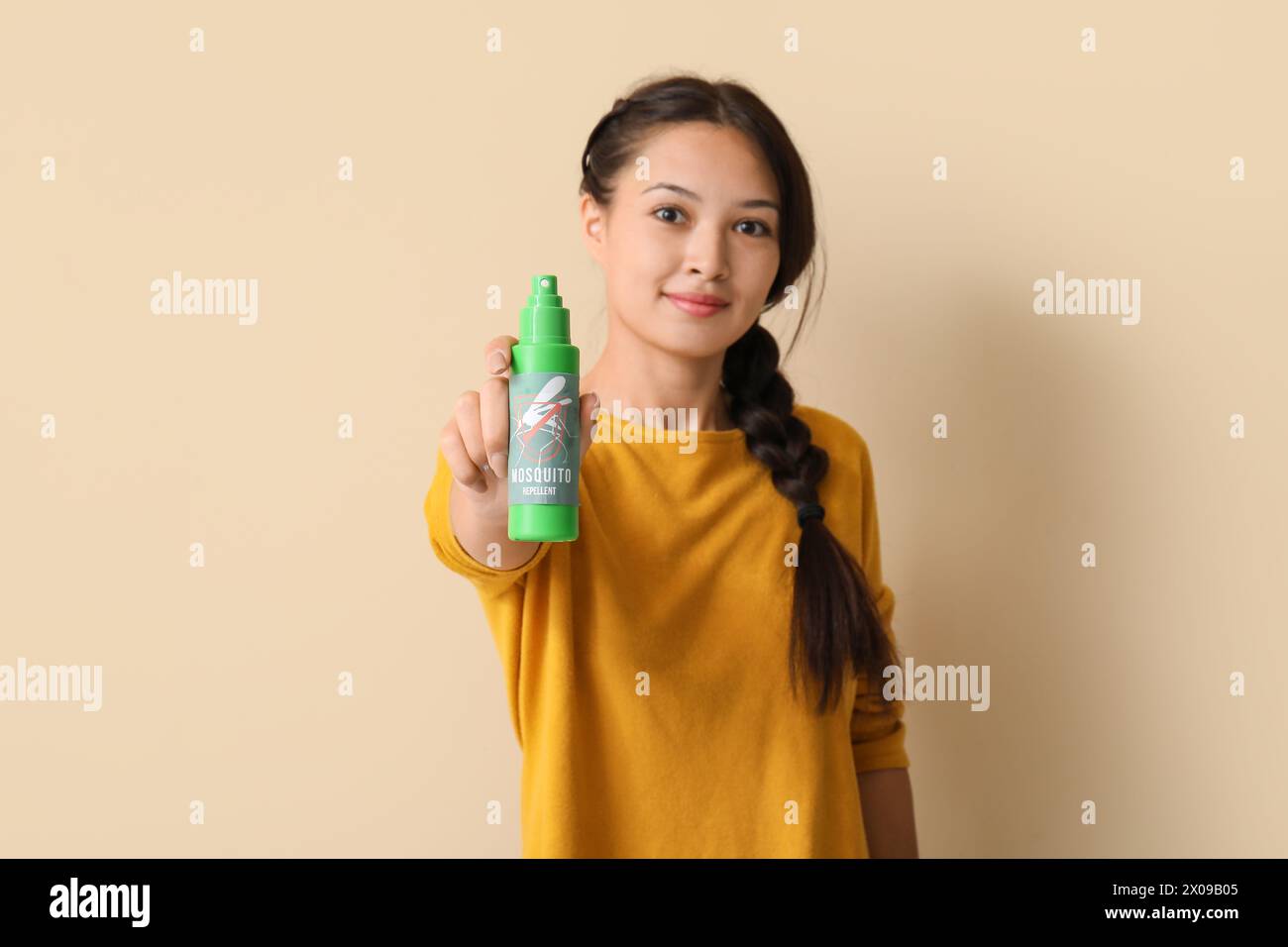 Beautiful young Asian woman with mosquito repellent spray on beige ...
