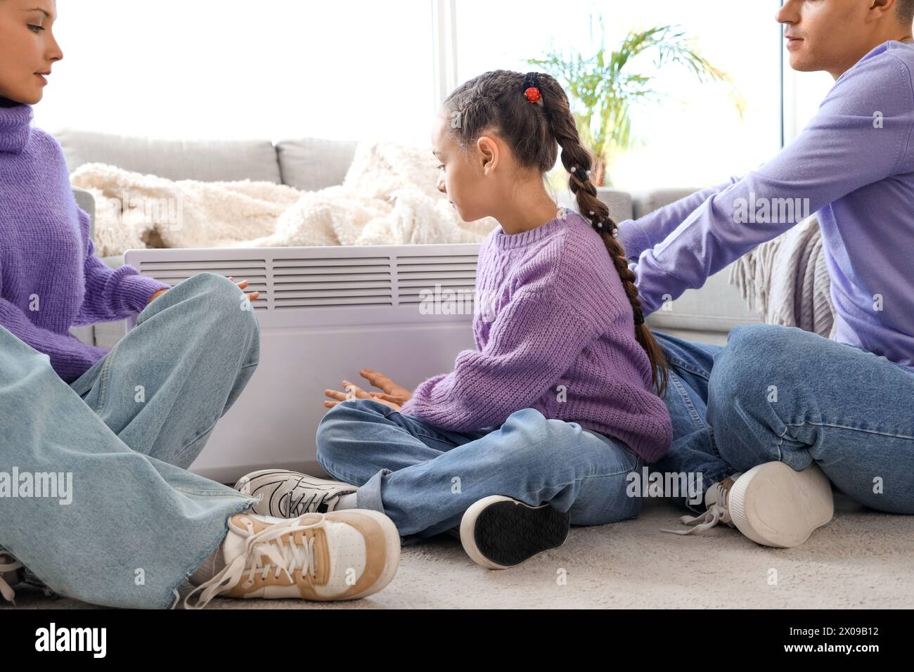 Frozen family warming near radiator at home Stock Photo - Alamy