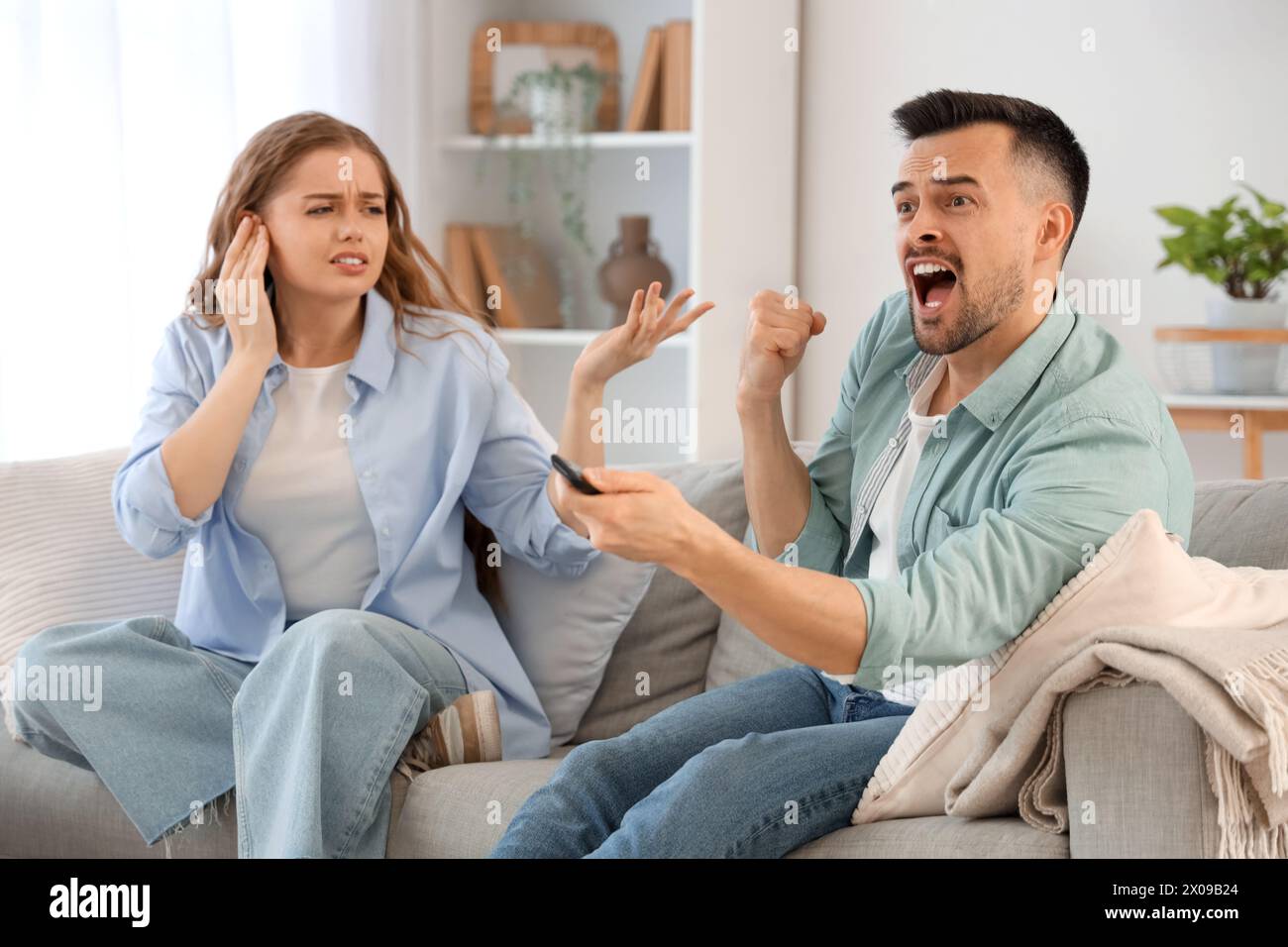 Young couple suffering from loud husband watching TV at home Stock ...