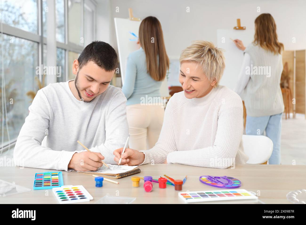 Mature art teacher helping student to draw at school Stock Photo - Alamy