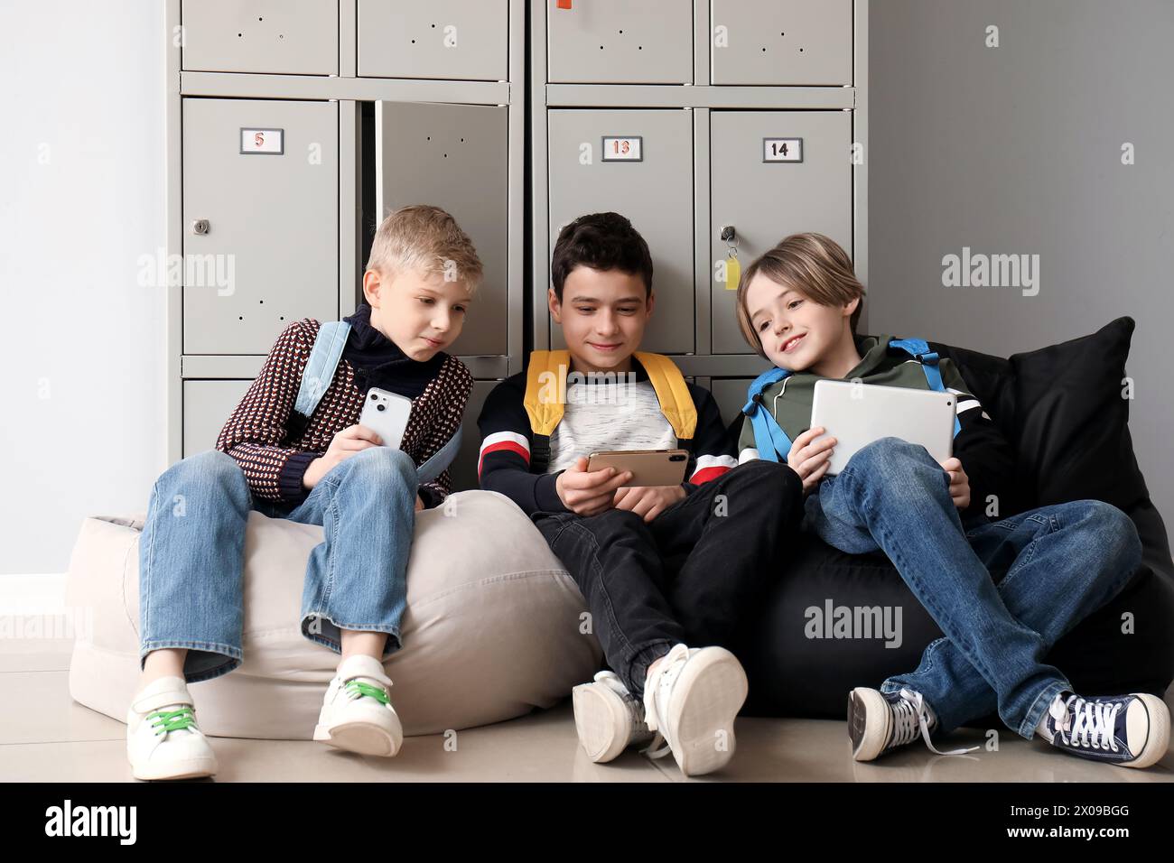 Little schoolboys using gadgets near locker at school Stock Photo - Alamy