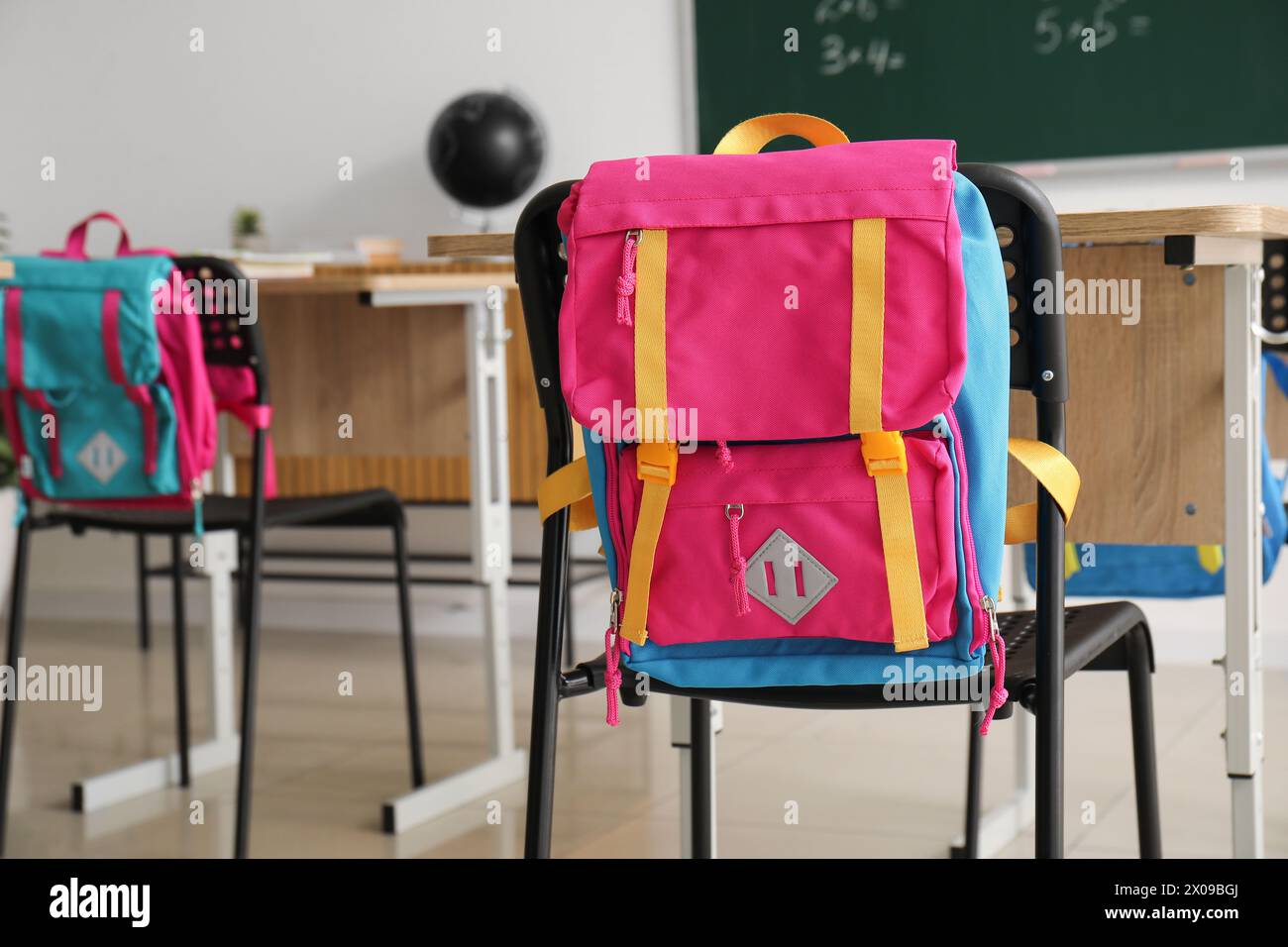 Schoolbag hanging on chair in classroom, closeup Stock Photo - Alamy