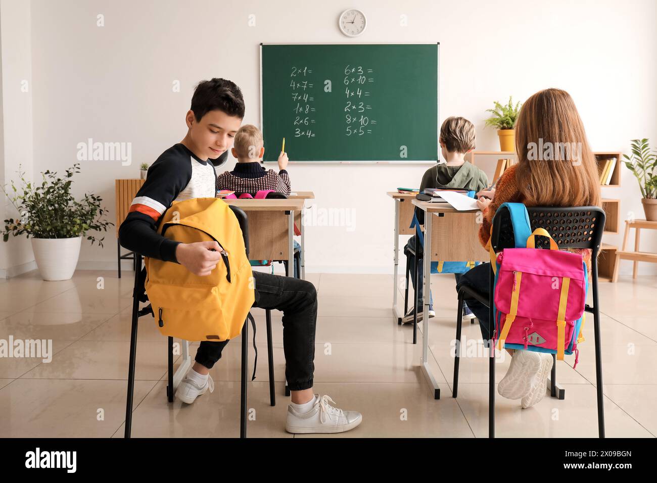Little pupils having Math lesson at desks in classroom, back view Stock ...