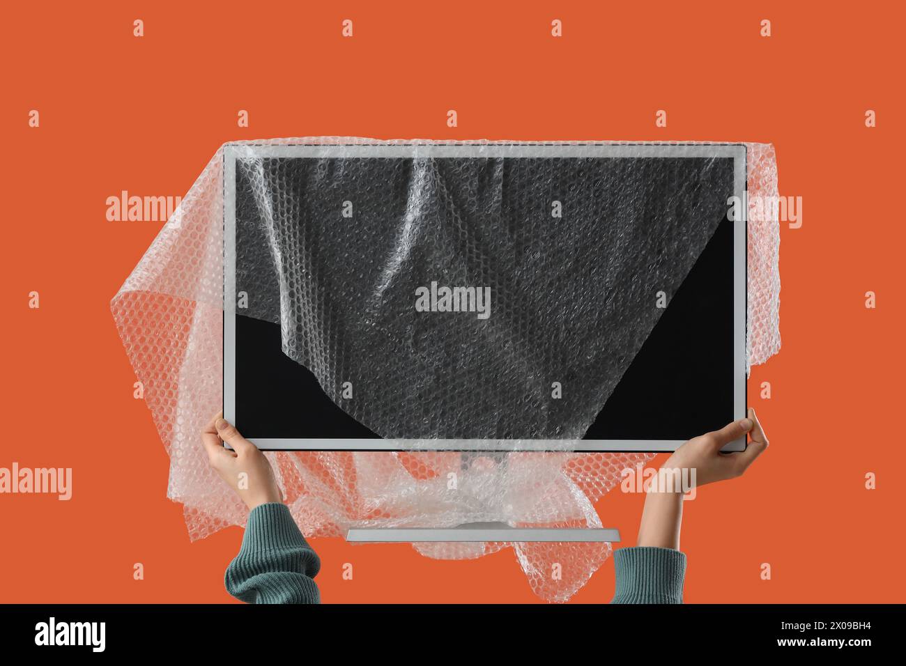 Woman with wrapped monitor on orange background Stock Photo - Alamy