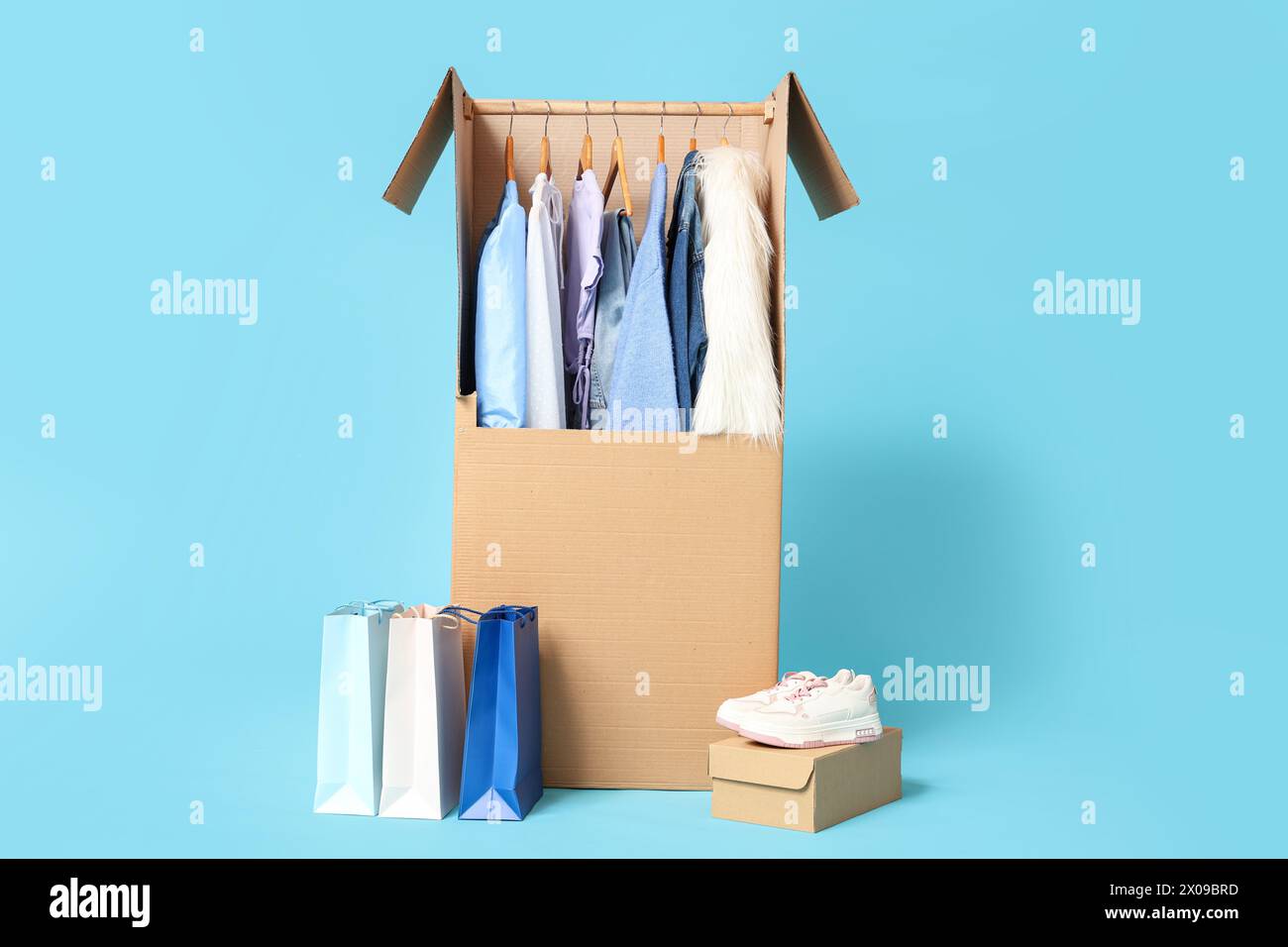 Wardrobe boxes with clothes and shopping bags on blue background Stock ...