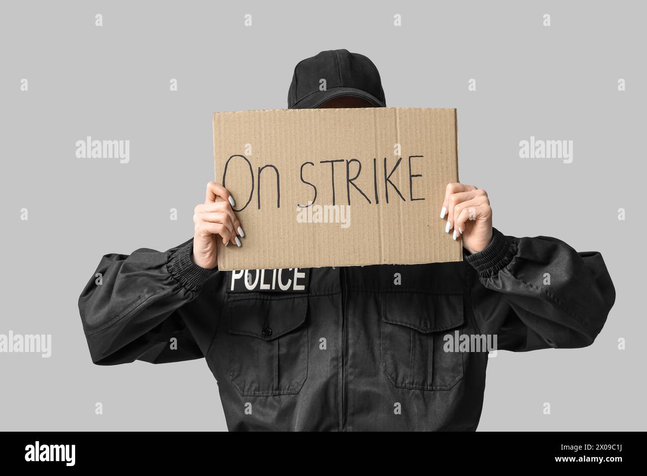 Protesting female police officer holding placard with text ON STRIKE ...