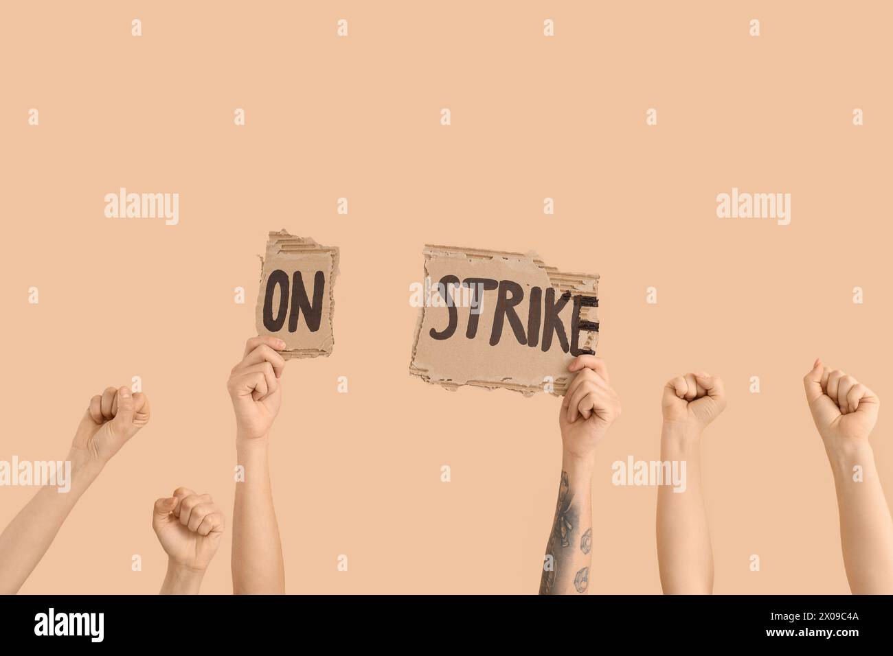 Protesting people holding placard with text ON STRIKE against beige ...