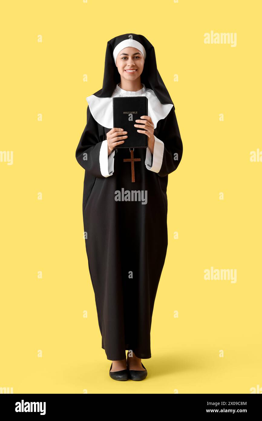 Young nun with Bible on yellow background Stock Photo - Alamy