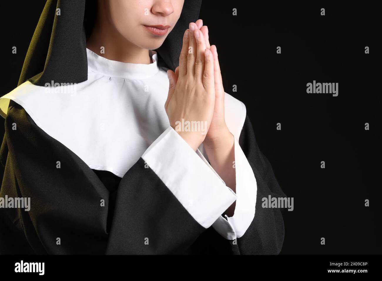 Praying young nun on black background Stock Photo - Alamy