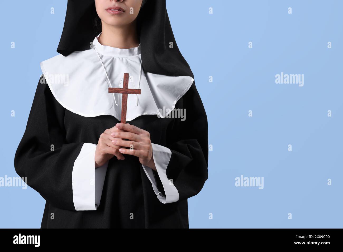 Young nun with cross on blue background Stock Photo - Alamy