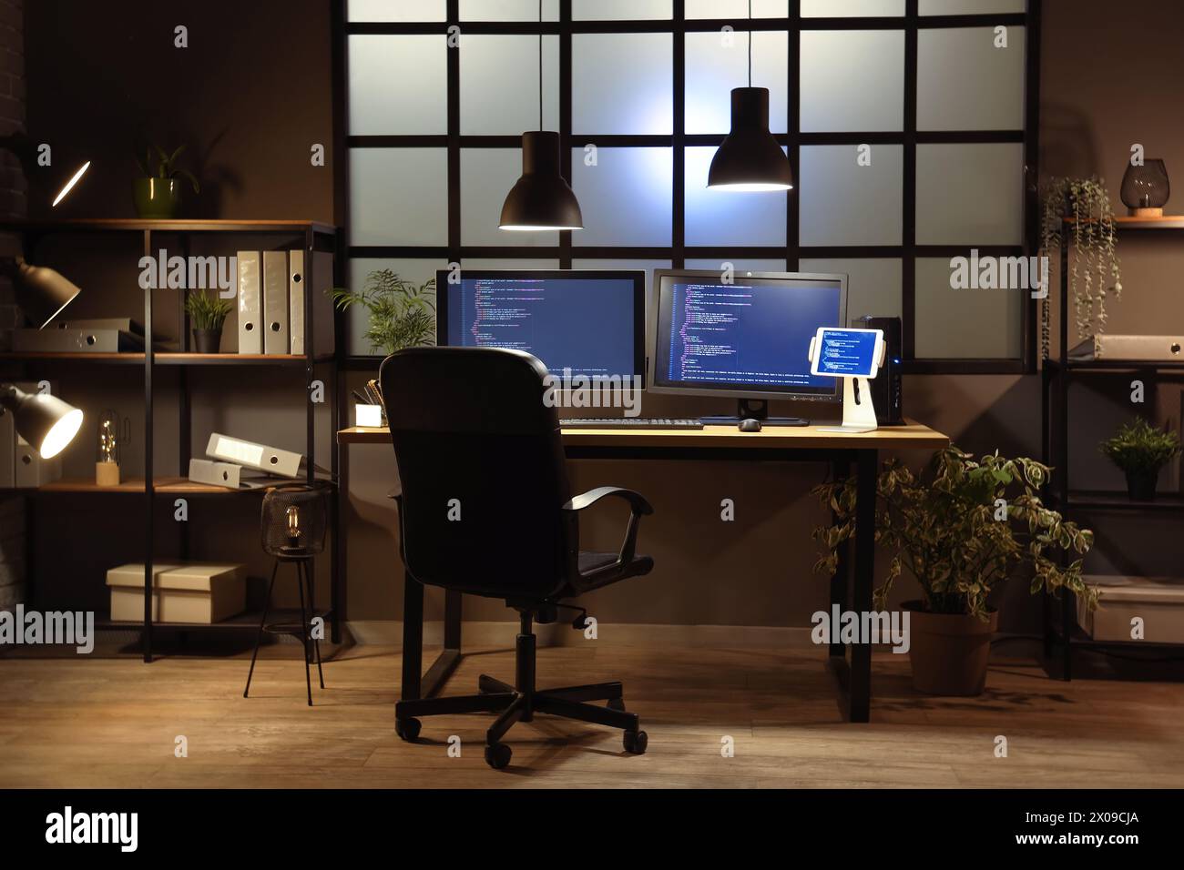 Interior of dark office with programmer's workplace and shelf units at ...