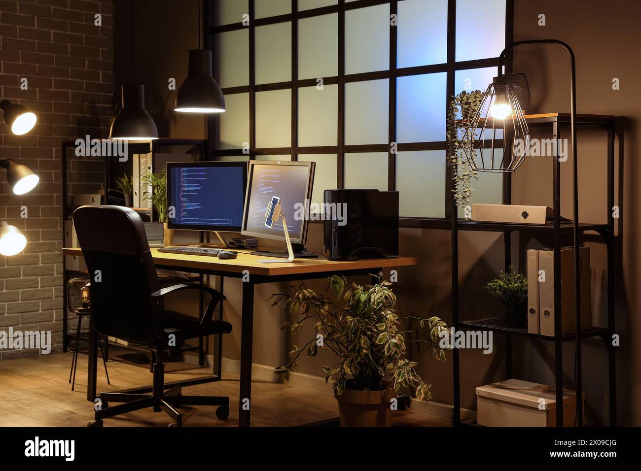 Interior of dark office with programmer's workplace and shelf units at ...