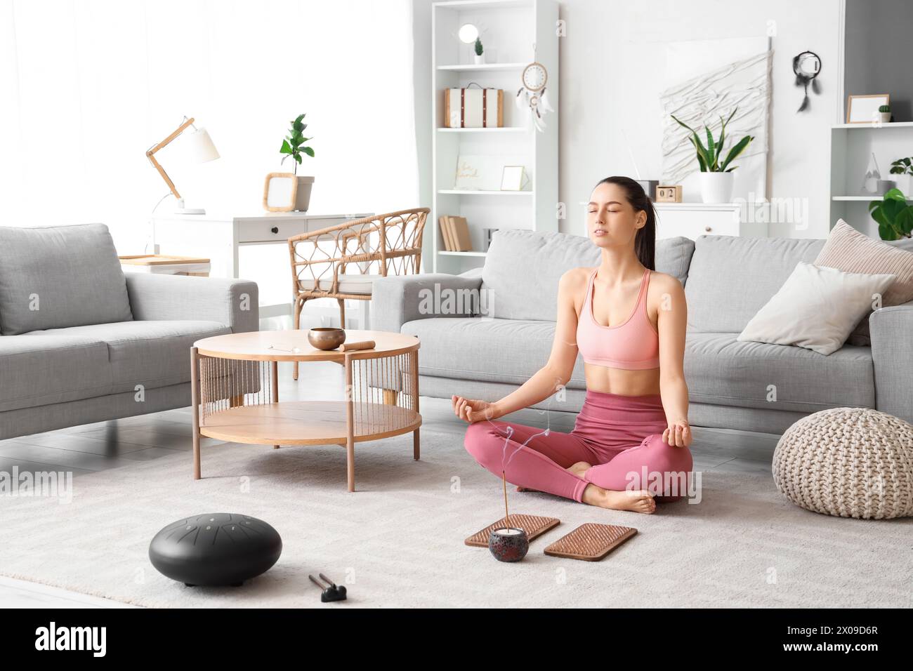 Sporty young woman with Sadhu board and aroma stick meditating at home ...