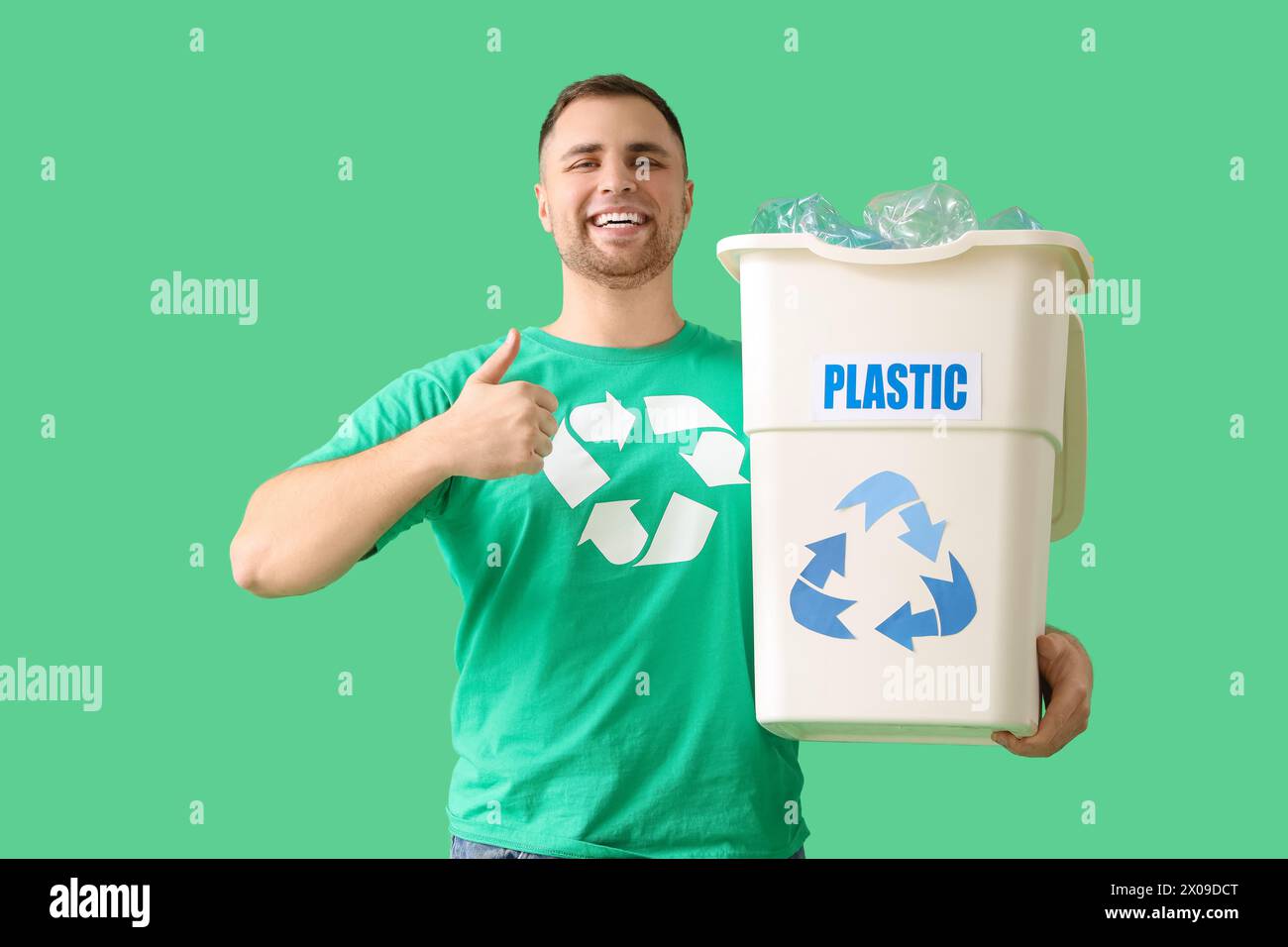 Male volunteer with recycle bin for plastic showing thumb-up on green ...
