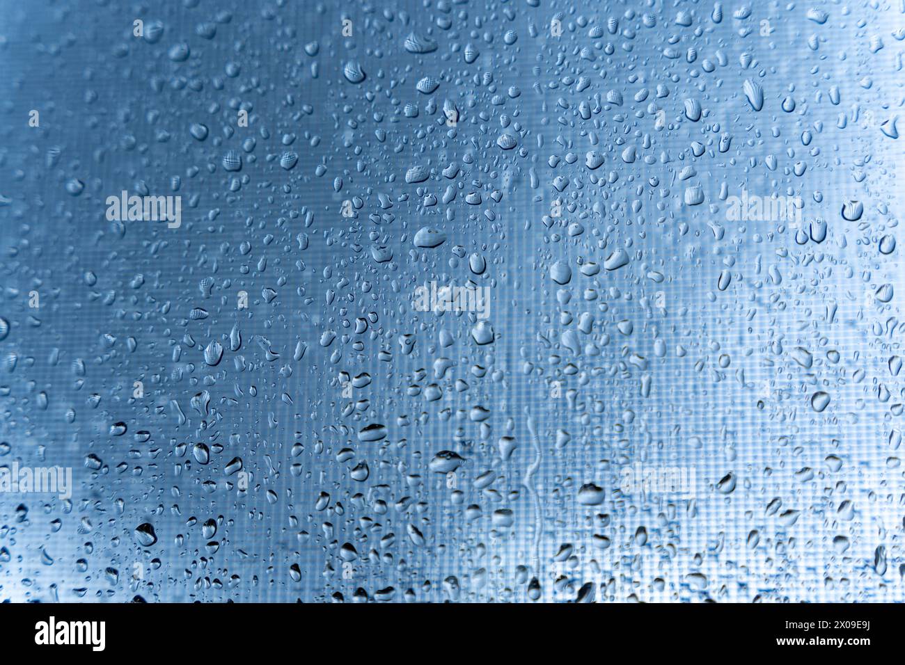 Close-up of raindrops on a window with a cityscape reflection in the ...