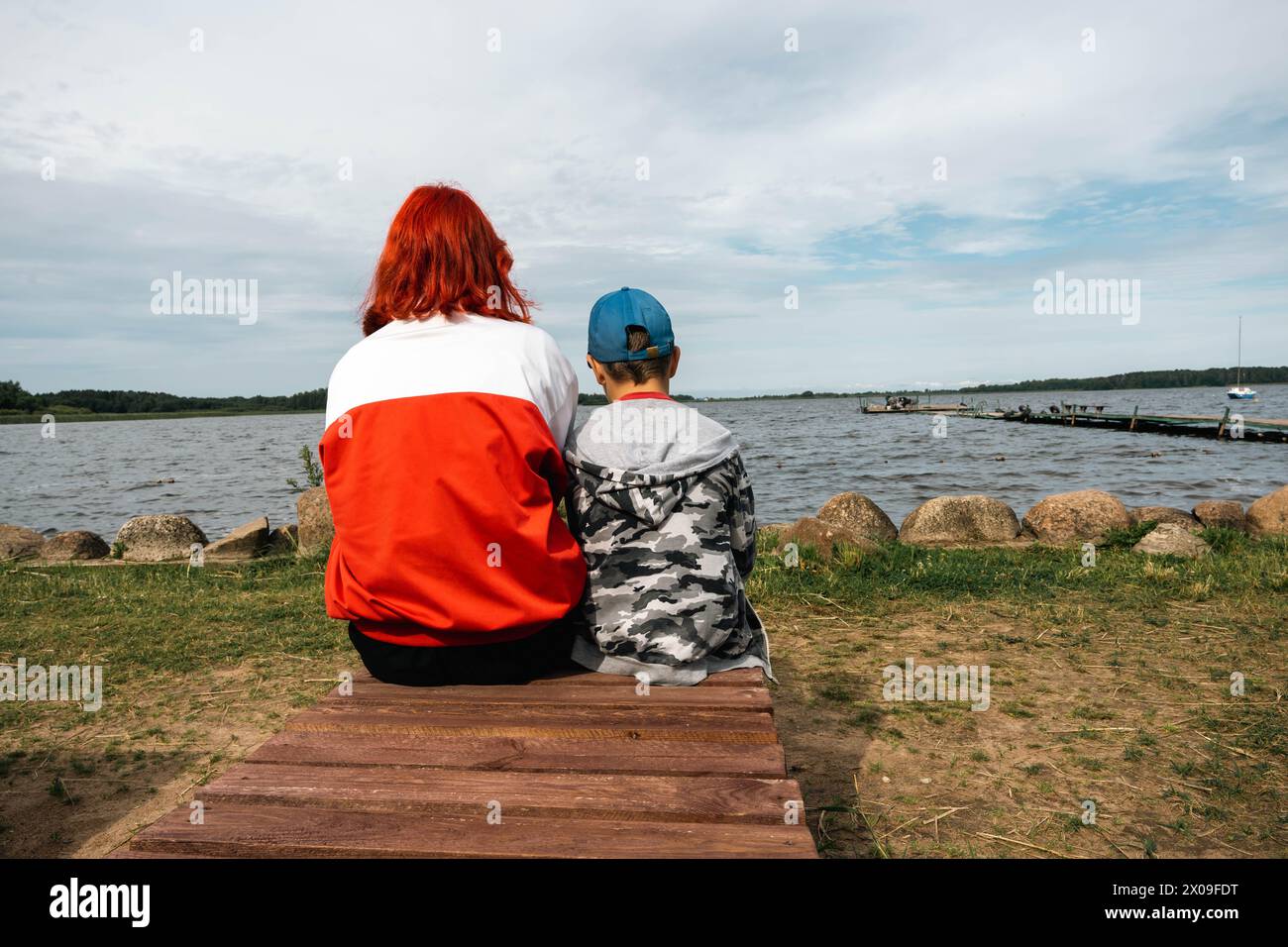 red-haired girl and her brother enjoying a quiet moment by the tranquil ...