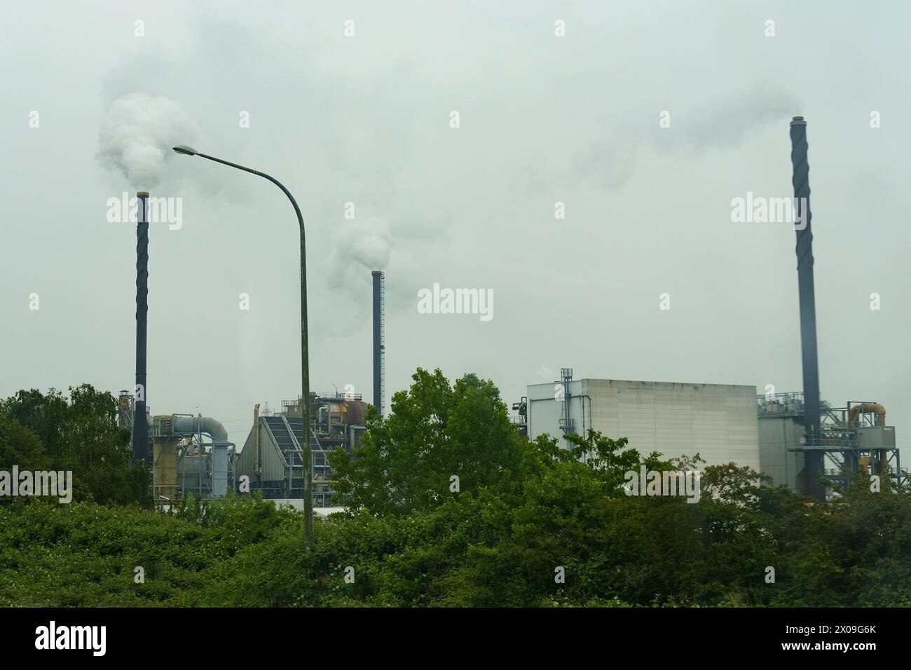 A factory billowing smoke from its tall stacks into the sky, showcasing ...