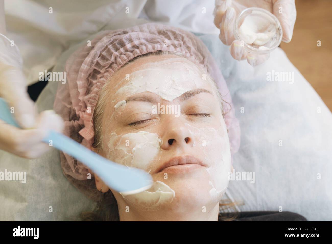 A woman getting a facial mask applied on her face at a beauty salon ...