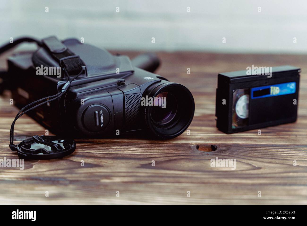 A vintage analog VHS video camera and a cassette with film on a wooden ...
