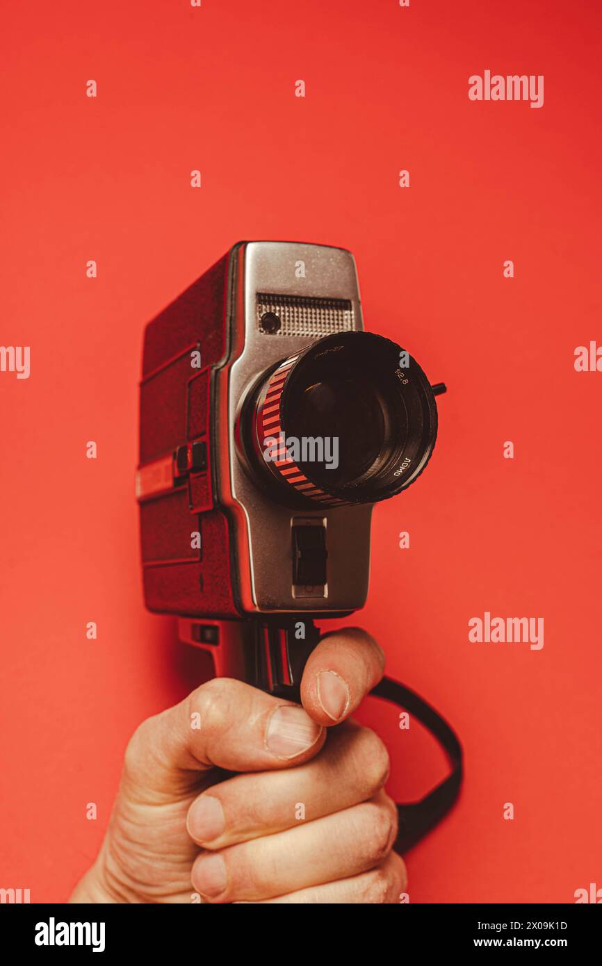 vintage portable movie camera in the operator's hand on a red ...