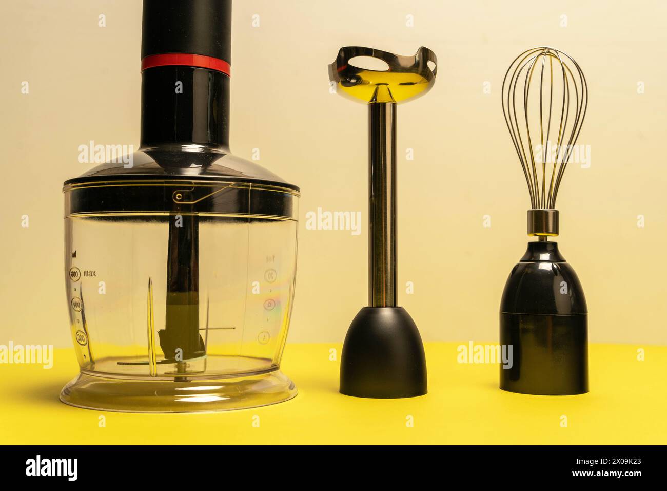 A blender, a whisk, and various whisk attachments arranged on a kitchen ...