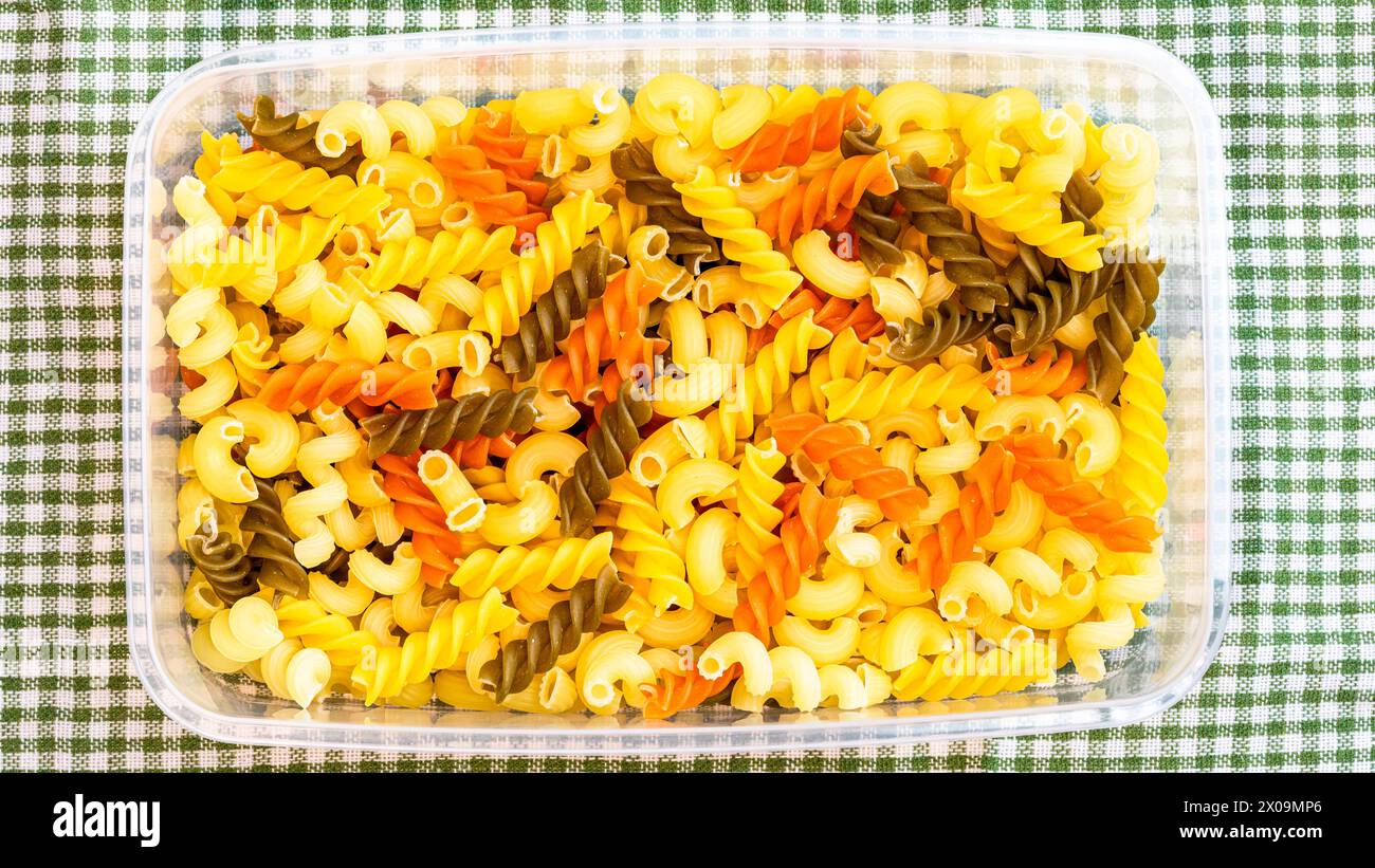 Tricolore fusilli, raw Italian pasta in plastic container, close up ...