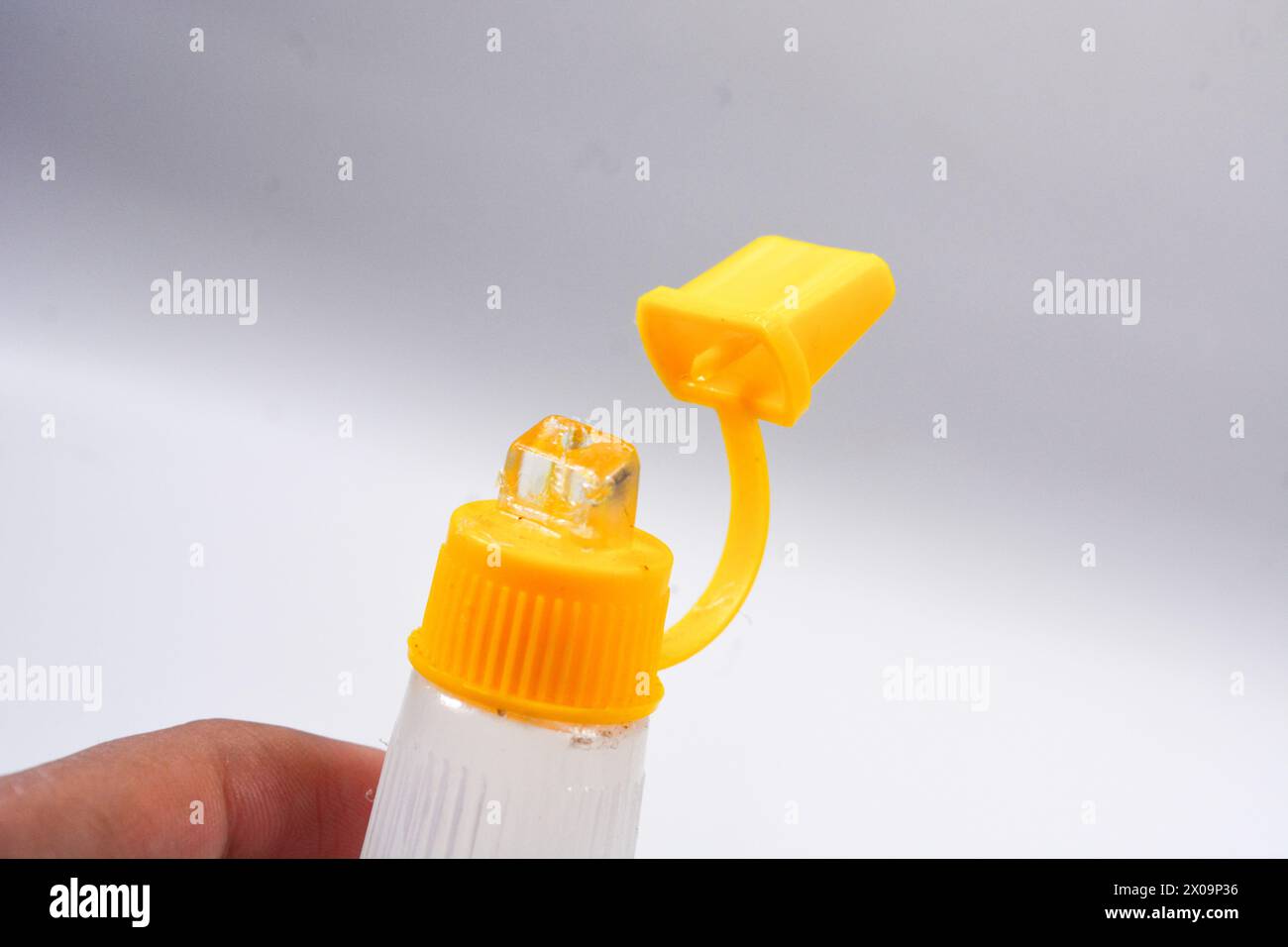 Human hand applying white glue on orange paper with scissor and stapler ...