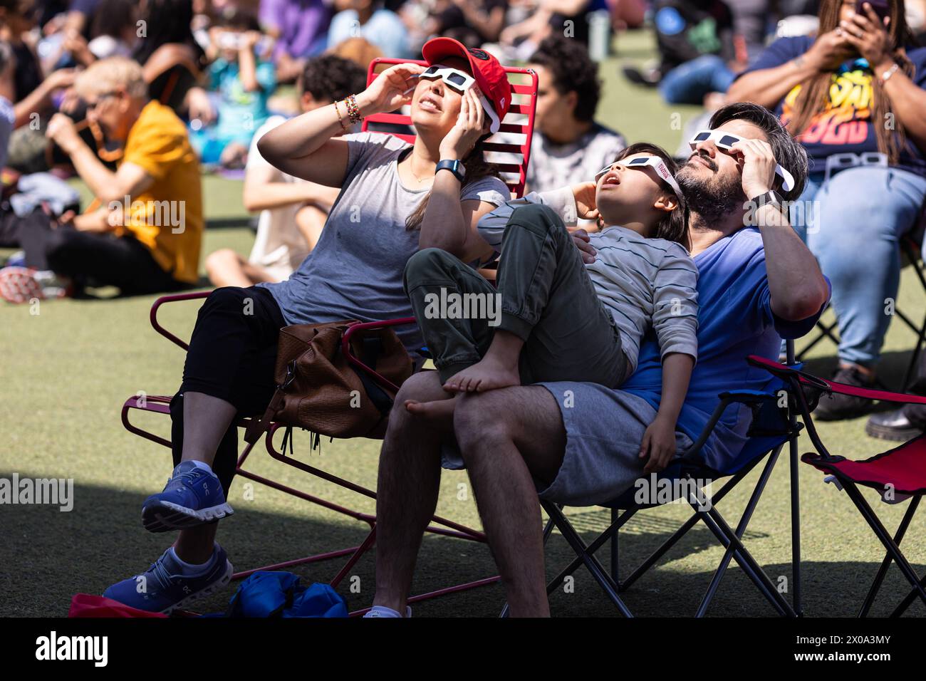Atlanta, GA / USA - April 8, 2024: A family wears special glasses to ...