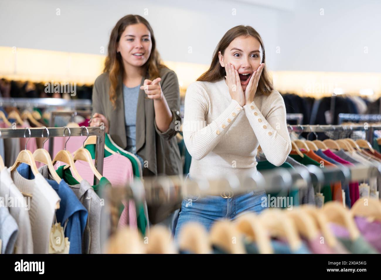 Happy girls pointing finger at new clothes in clothing store Stock ...