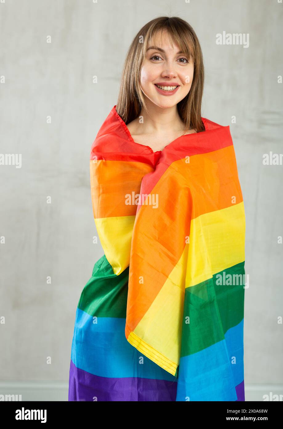 Happy young woman holding transgender flag against unicoloured ...