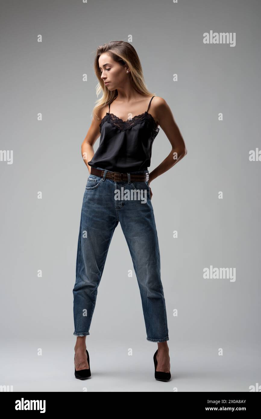 Chic and effortless, her stance in jeans and a lacy black top conveys a ...