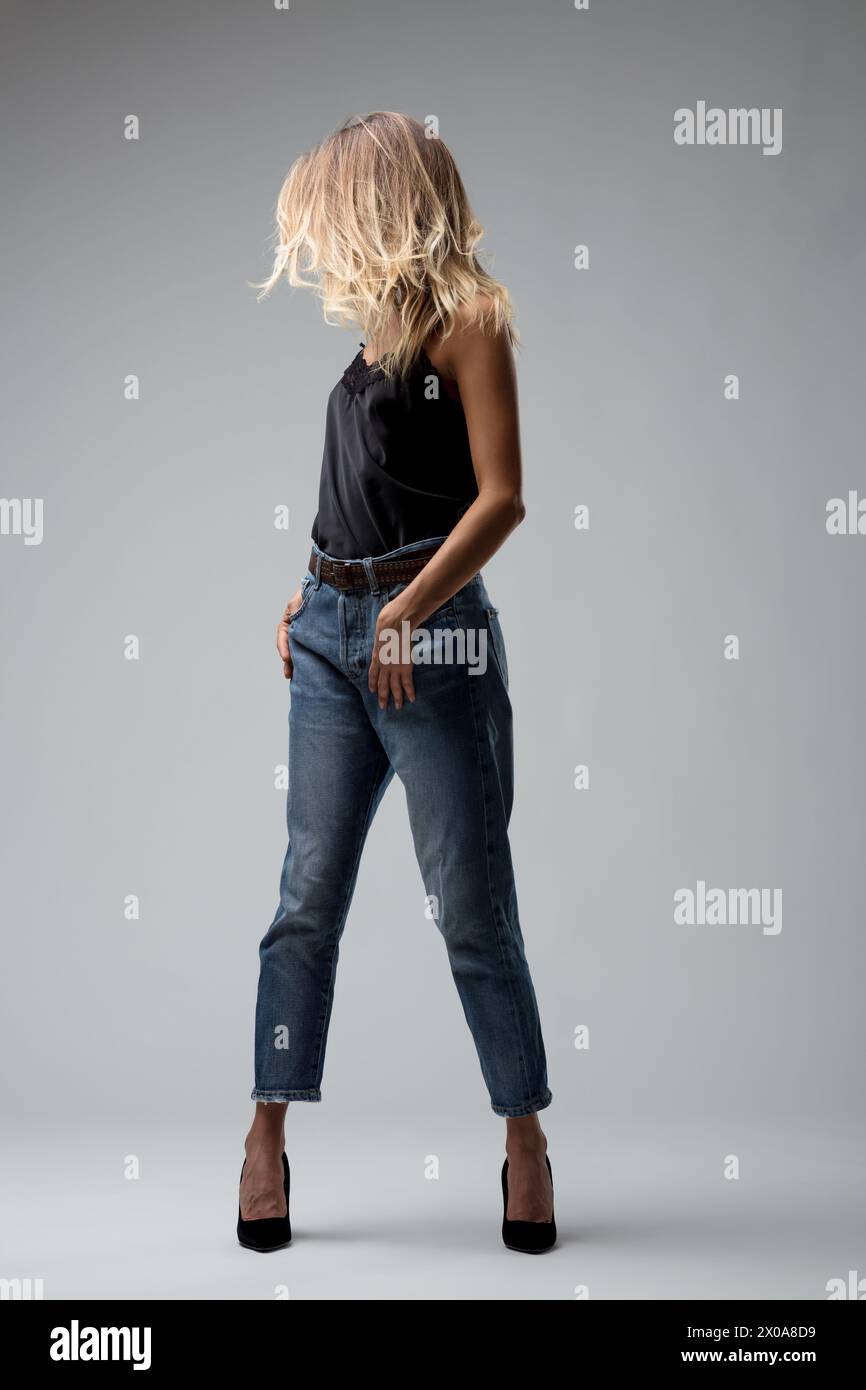 Looking off into the distance, she stands in jeans and heels, her pose ...