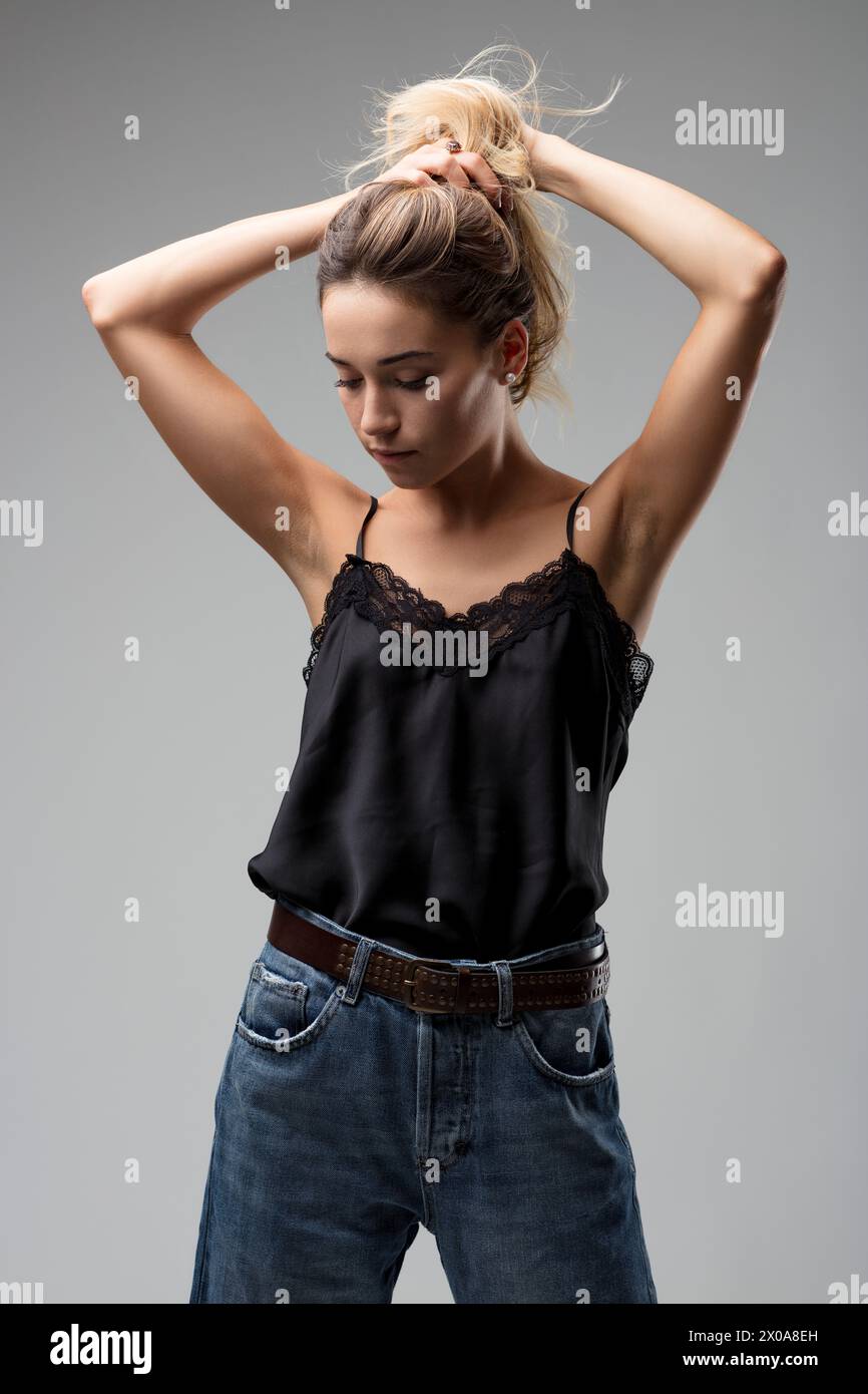 Poised in the act of styling her hair, the lace and denim-clad woman ...