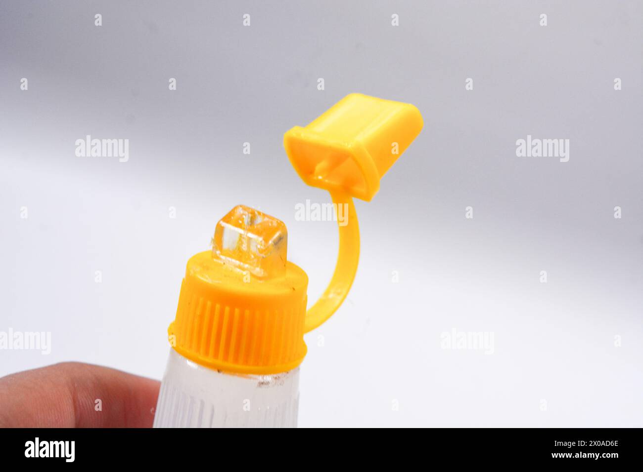 Human hand applying white glue on orange paper with scissor and stapler ...