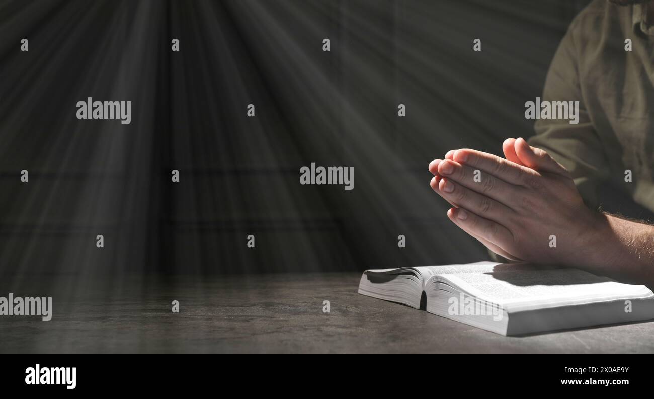 Religion. Christian man praying over Bible at table, closeup. Banner ...