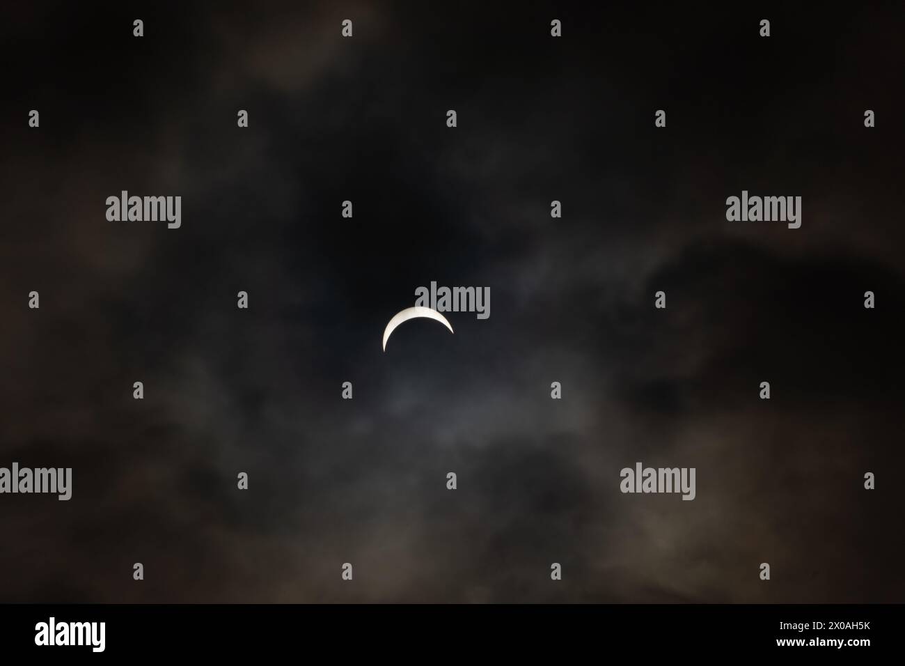 Partial solar eclipse - moon covers sun, dark clouds, celestial drama ...