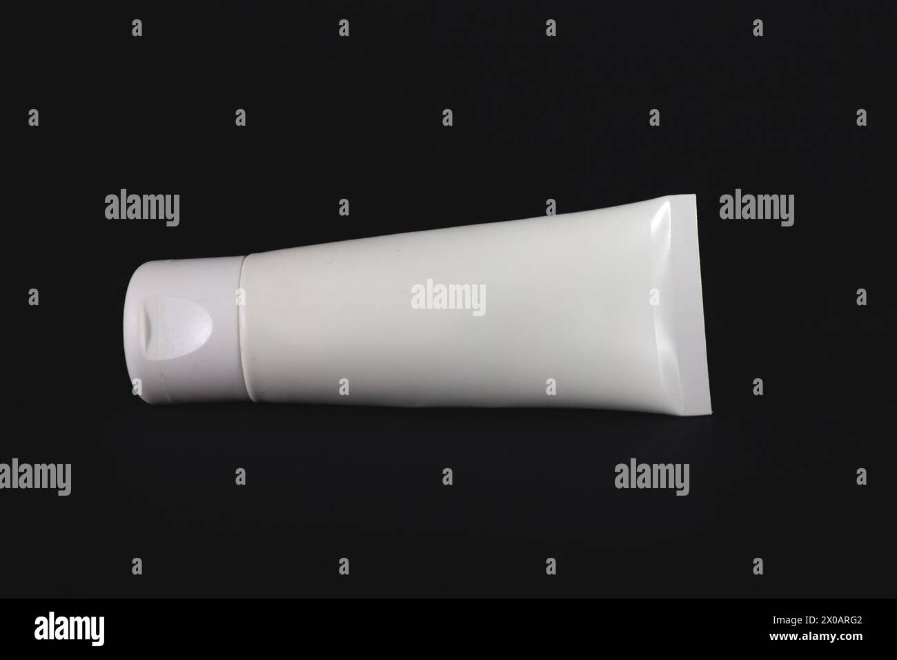 This image features a minimalist white tube against a stark black ...