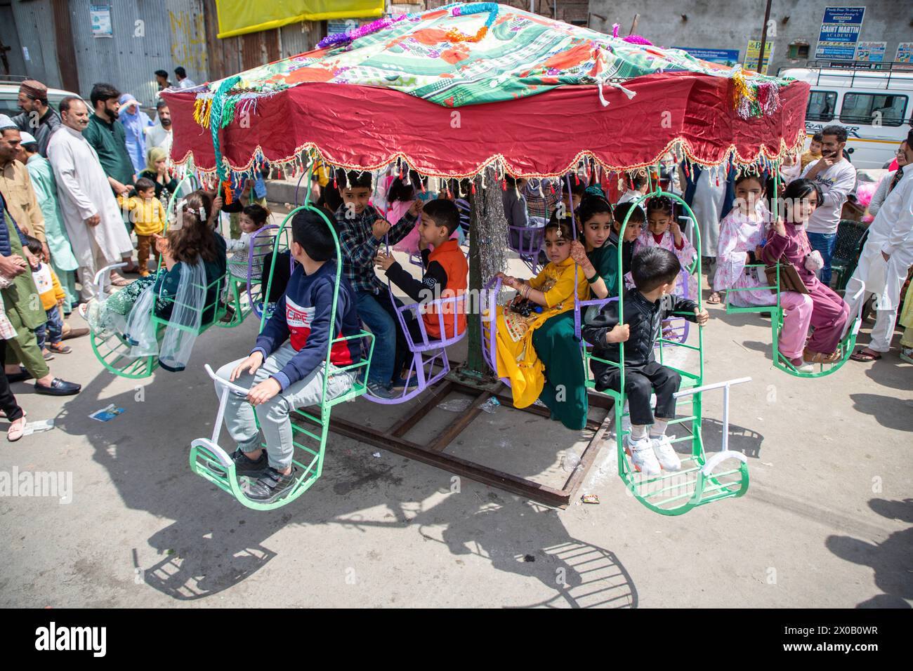 Srinagar, India. 10th Apr, 2024. Kashmiri children ride a swing on the first day of Eid-Al-Fitr ...