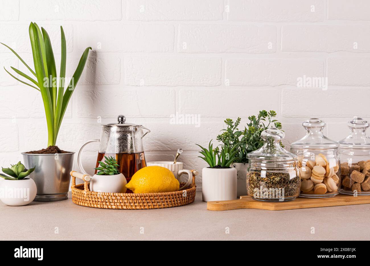 Stylish kitchen background with glass tea pot, lemon, cup, tea jars ...