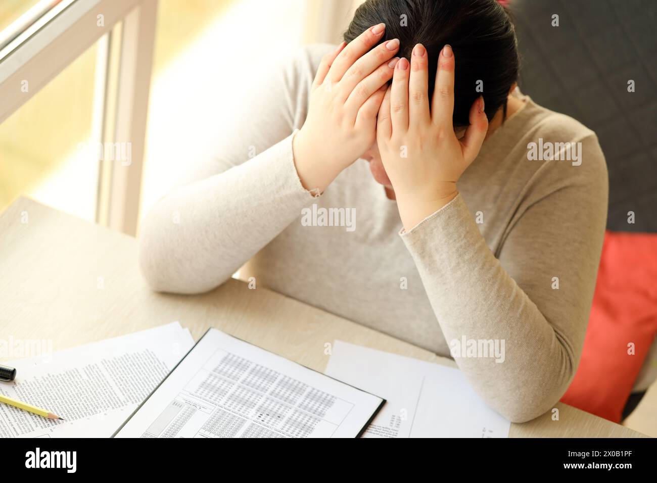 Sad female student testing in exercise and fill exam paper sheet with ...