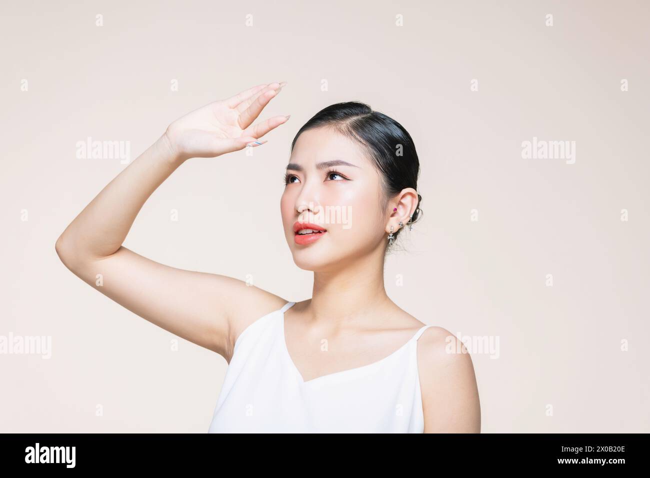 Woman covering her face from sun with her hand while standing against ...