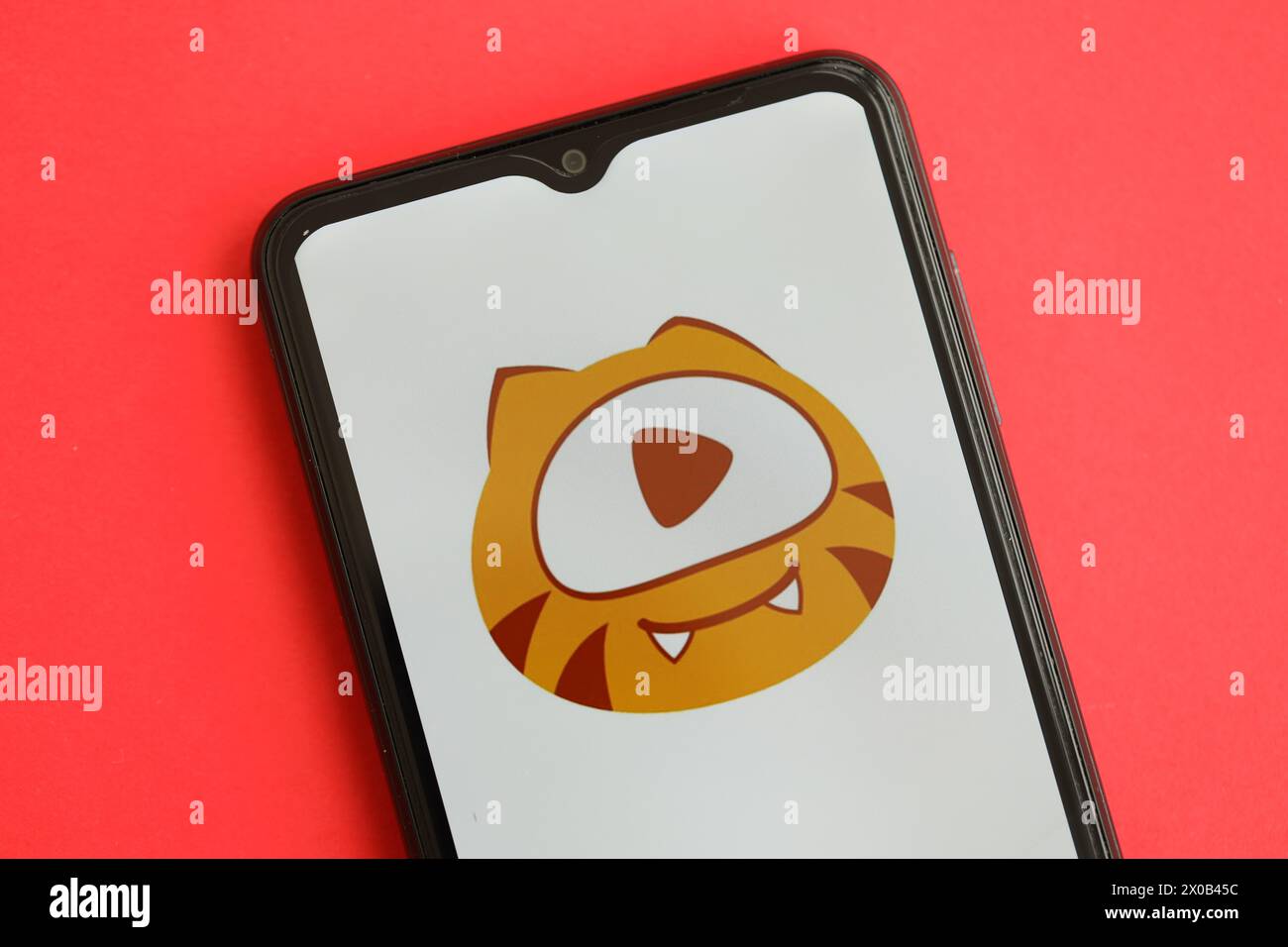 KYIV, UKRAINE - APRIL 1, 2024 Huya icon on smartphone screen on red table close up. iPhone ...