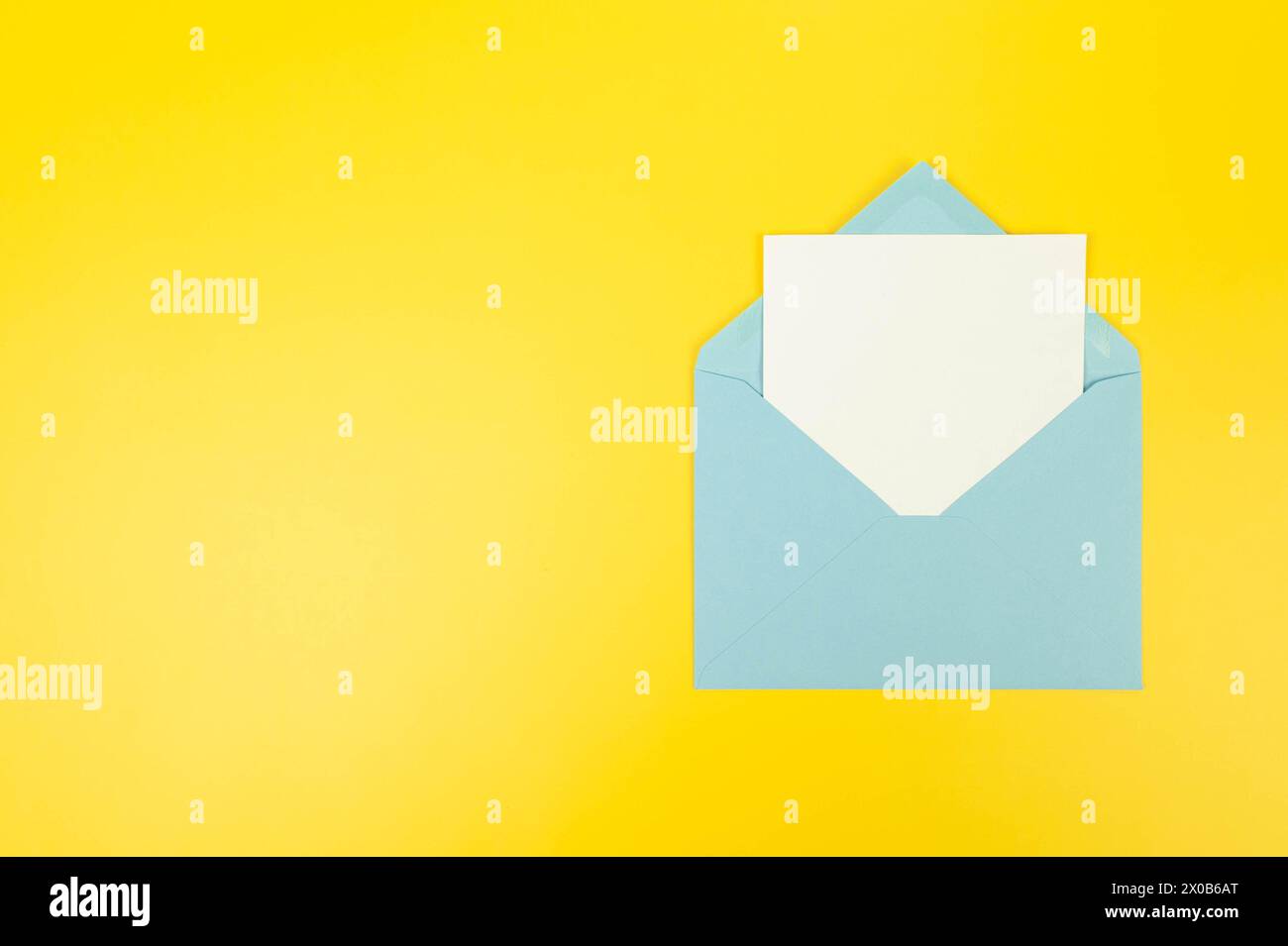 Top view of light blue envelope, white card on yellow background. Post ...