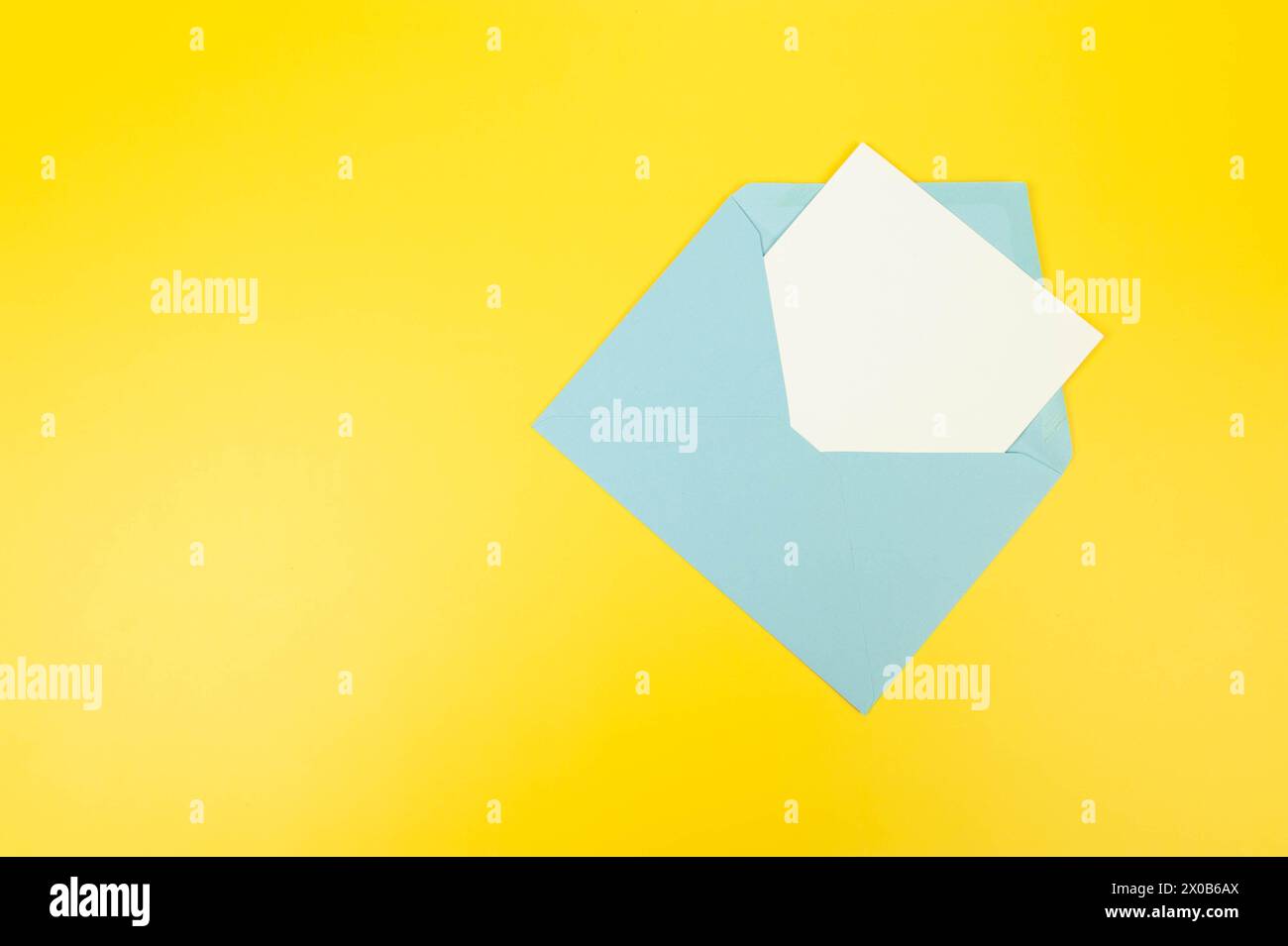 Top view of light blue envelope, white card on yellow background. Post ...