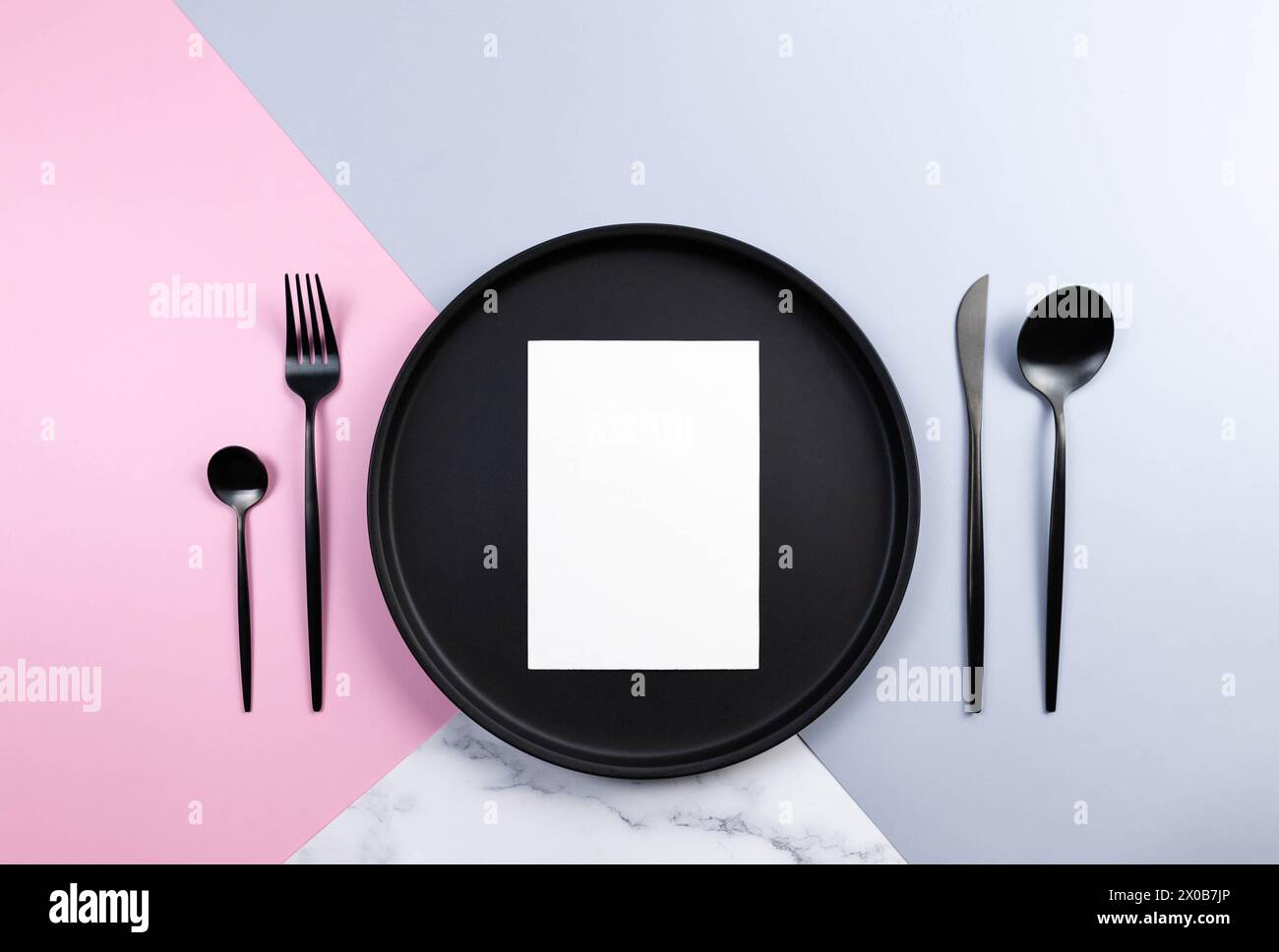 Top view of black plate and cutlery, white card on colourful background ...